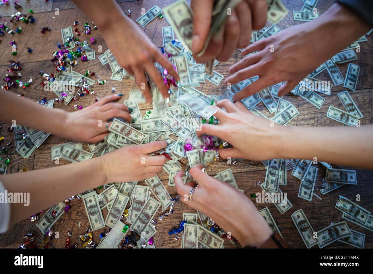 Several pairs of hands pick up dollar bills from the floor. Concept ...