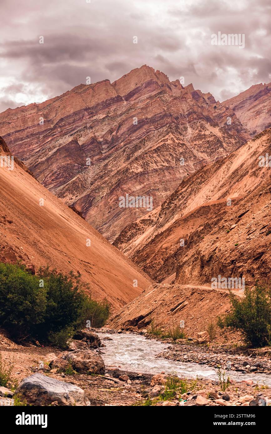 A stream flows in between the rocky and rugged mountains of the Zanskar ...