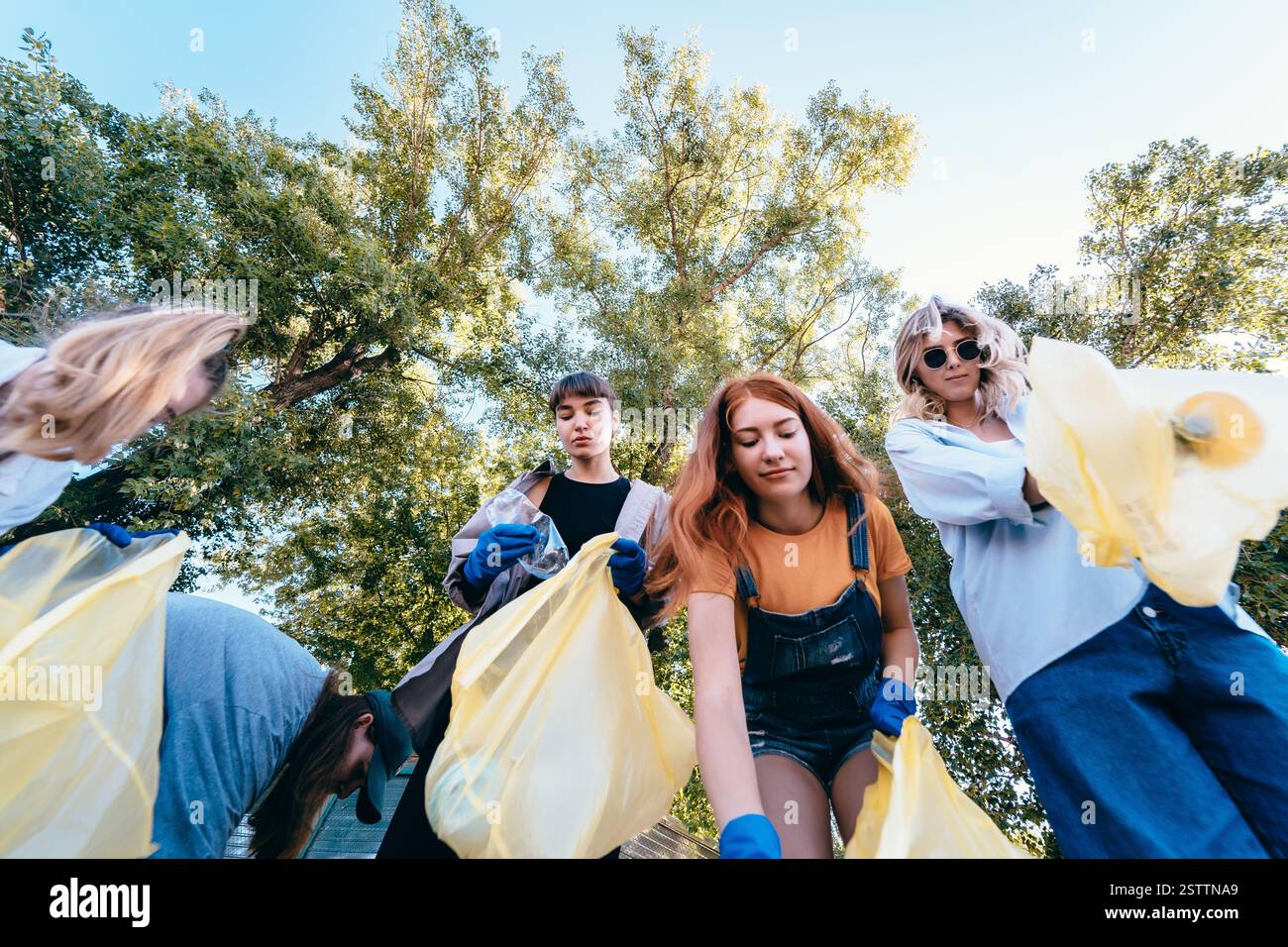 Group of activists friends throw a lot of garbage in a bag. Bottom-up ...
