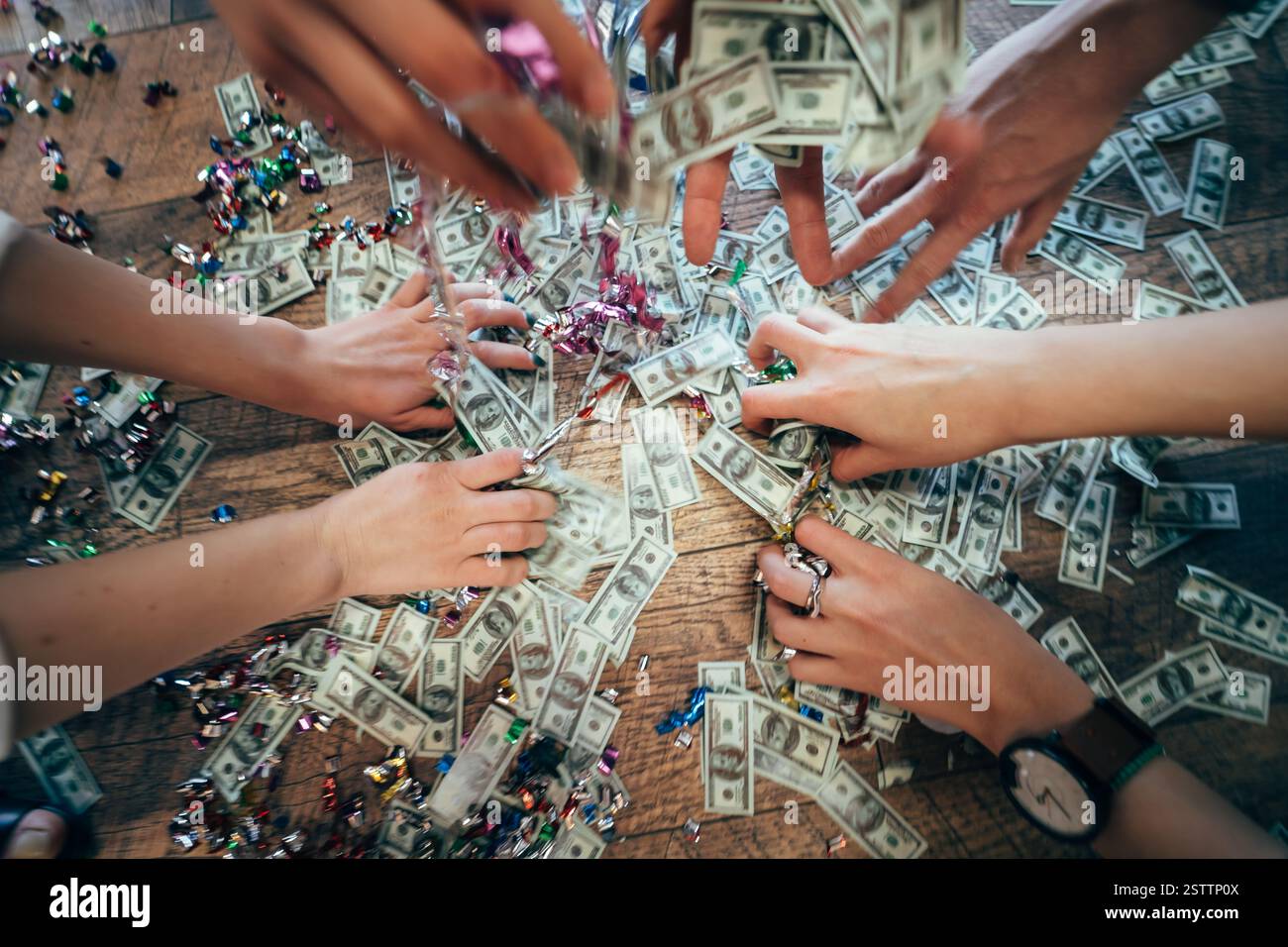 Several pairs of hands pick up dollar bills from the floor Stock Photo ...