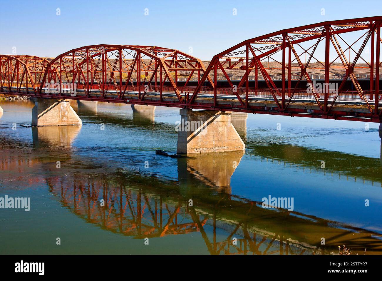 Bridge spans a river with a reflection of the bridge in the water. The ...