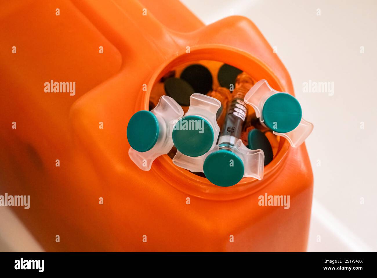 Close-up of used medical syringes with green safety caps inside an ...