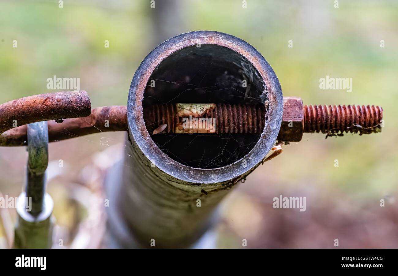 Close-up of a rusted metal pipe with cobwebs and corrosion in a natural ...