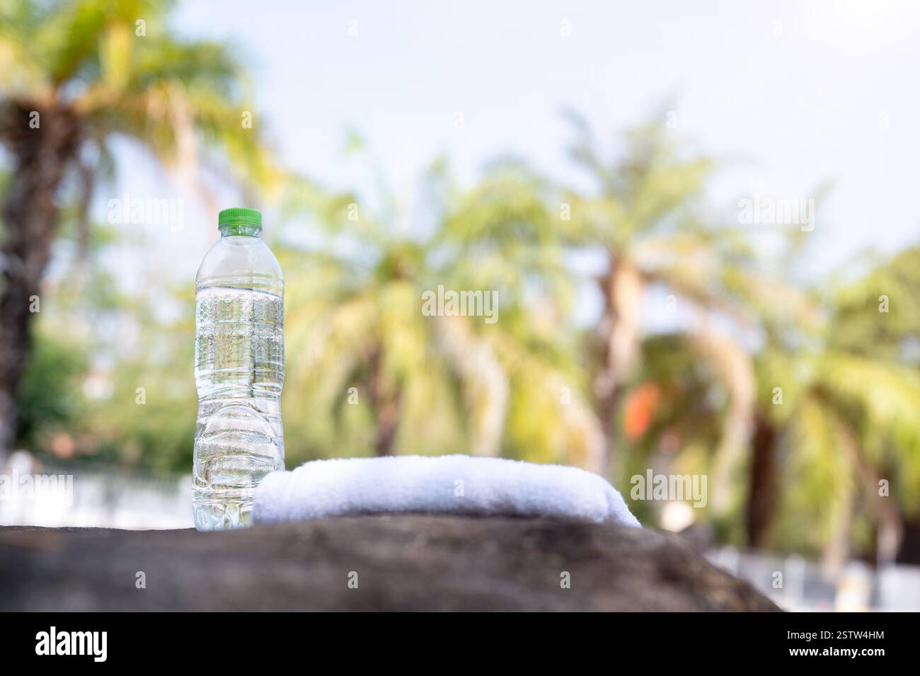 A water bottle place beside towel on the stone bench with blurry ...