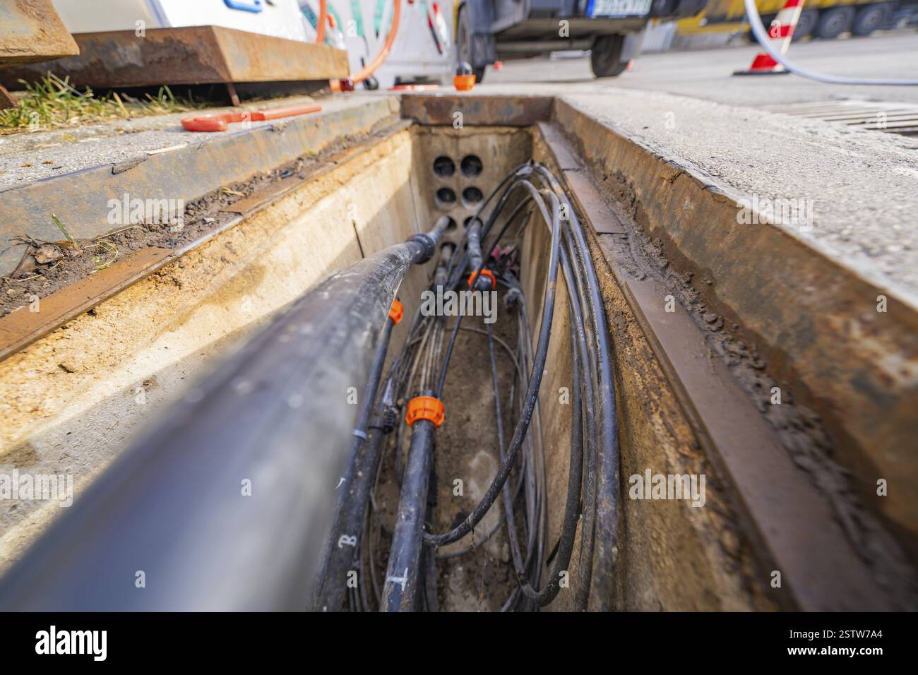 Open manhole with numerous cables and pipes at a construction site ...