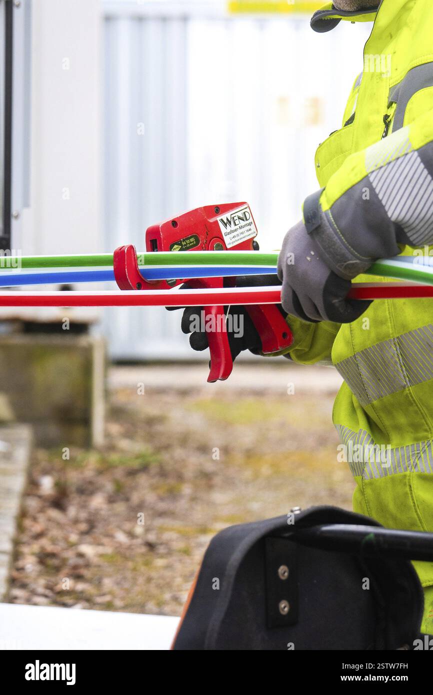 Person in protective clothing at work with coloured cables and tools ...