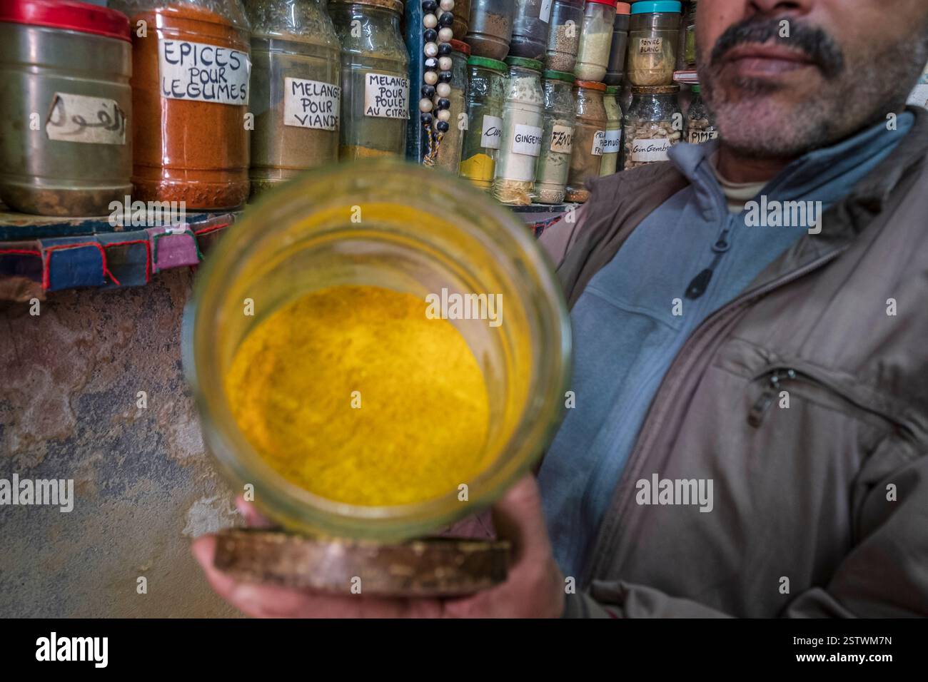Spice seller holding a jar of turmeric Stock Photo - Alamy
