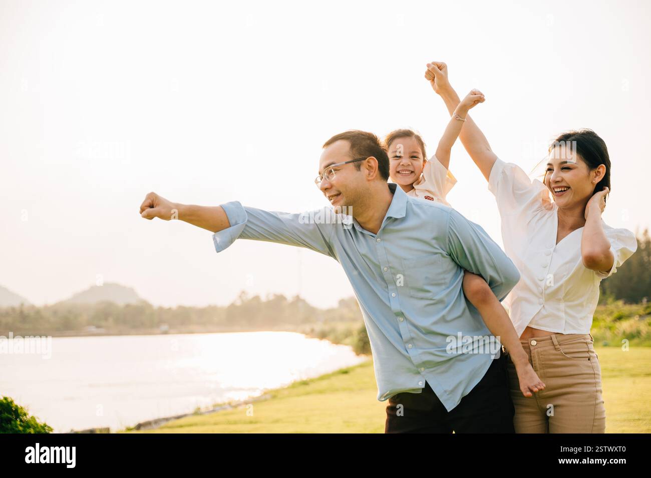 Asian family child girl piggyback riding back on father raising hands ...