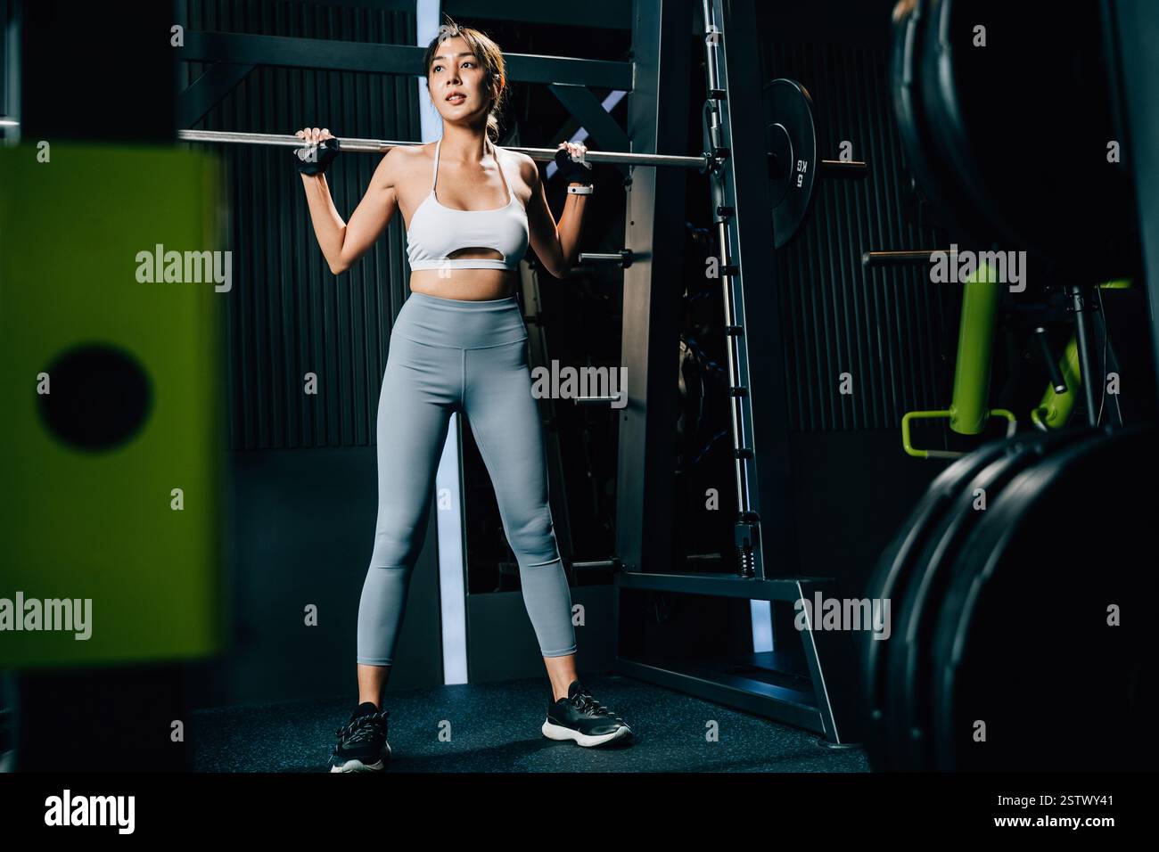 Asian muscular woman guy performing a squat exercise legs heavy weights with a barbell in gym ...