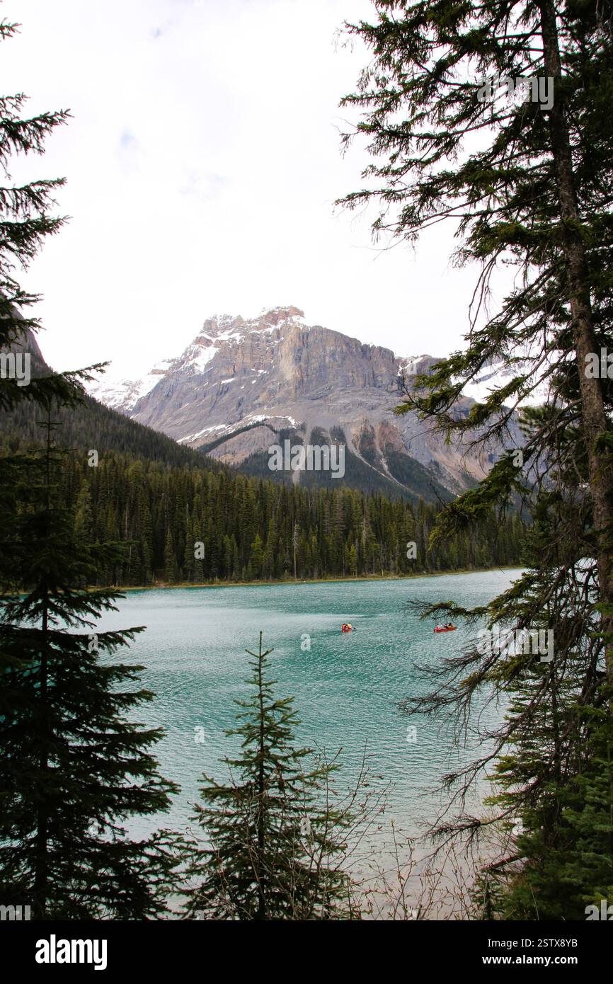 A serene natural landscape featuring a turquoise lake, evergreen trees ...