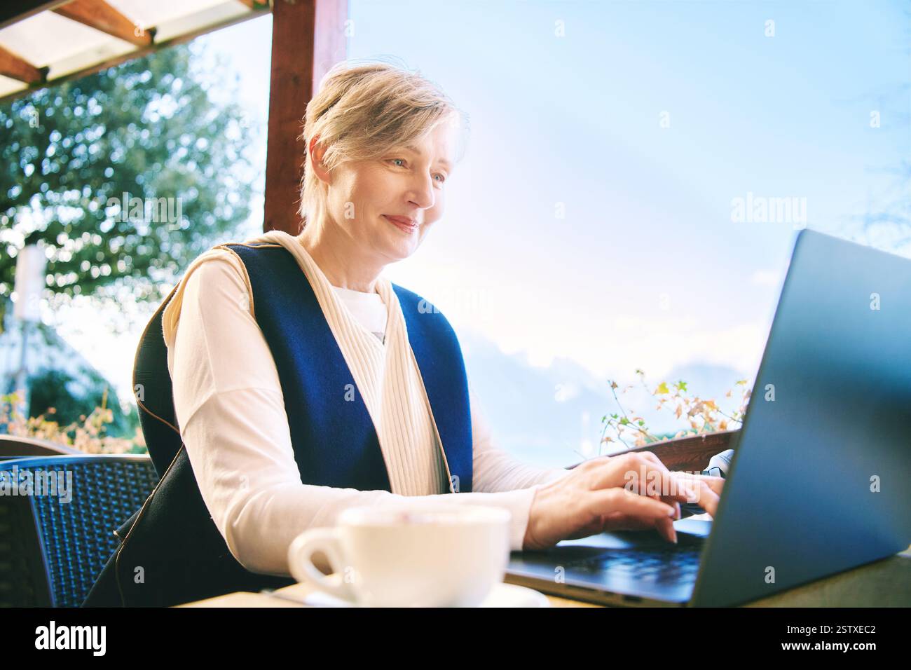 Outdoor portrait of mature 55 - 60 year old woman working with laptop ...