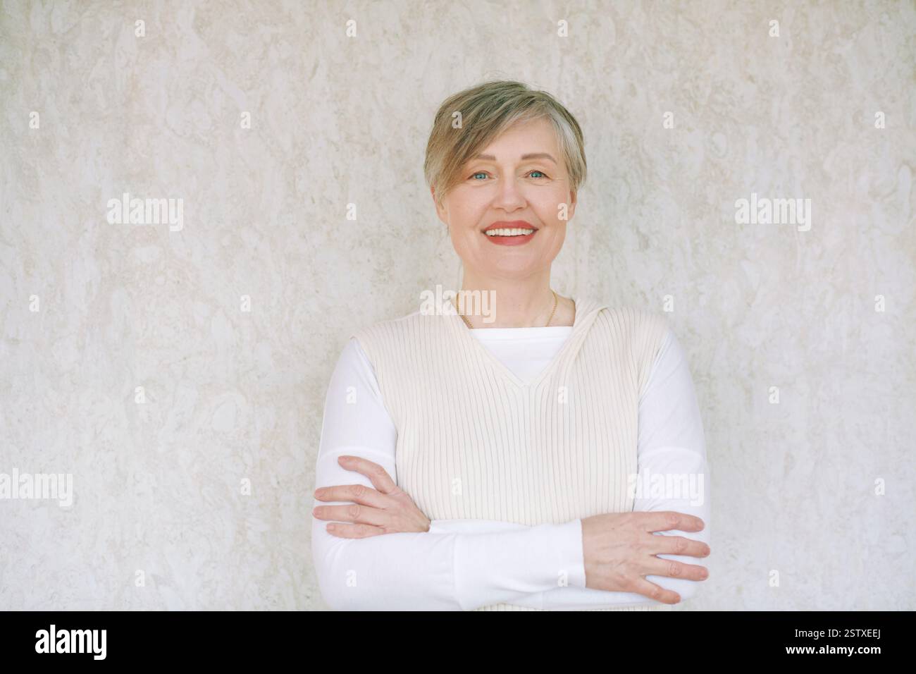 Portrait of mature 55 - 60 year old woman with grey hair, arms crossed ...