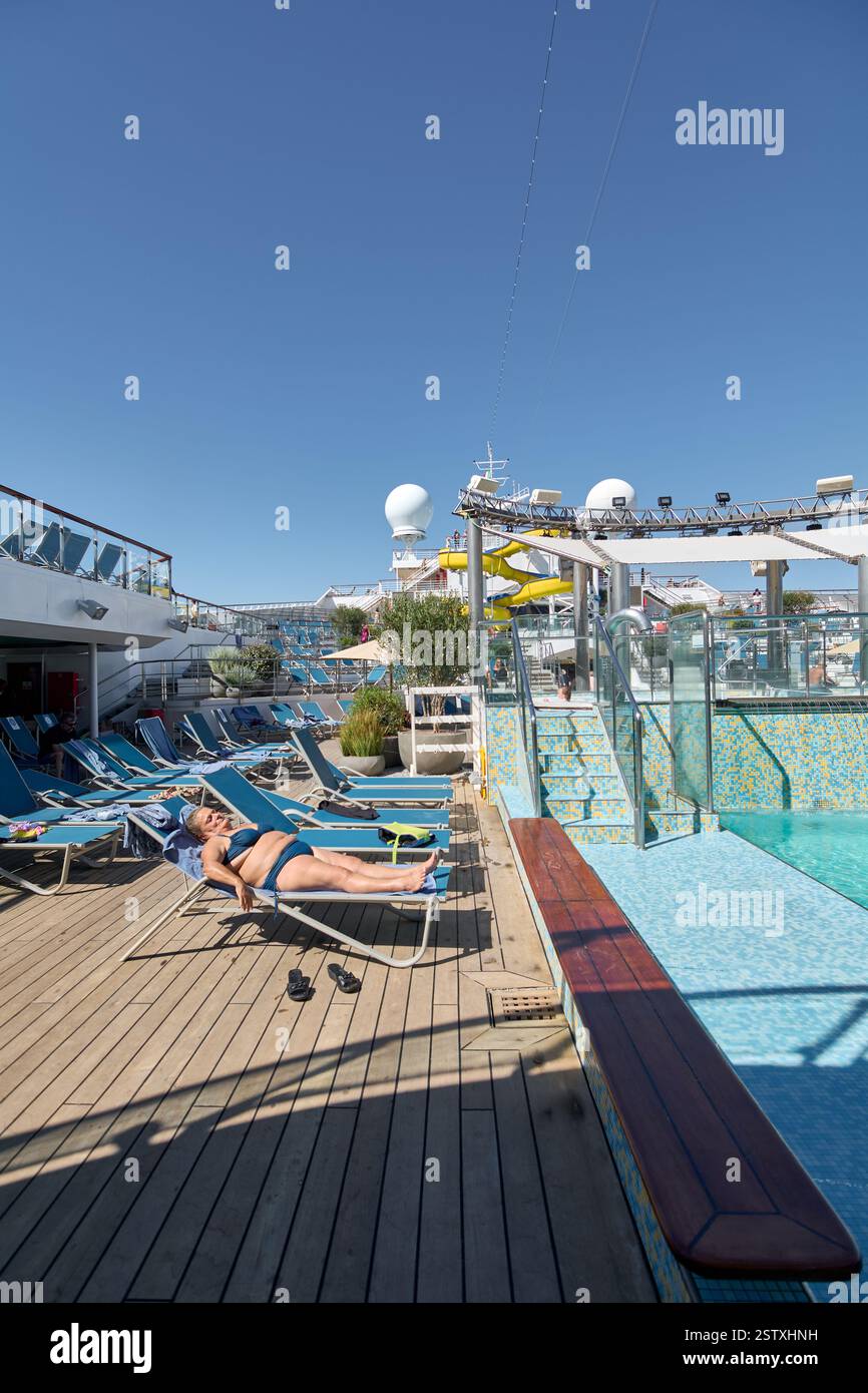 Catania. Italy - February 20, 2025: Woman sunbathing on a lounge chair ...