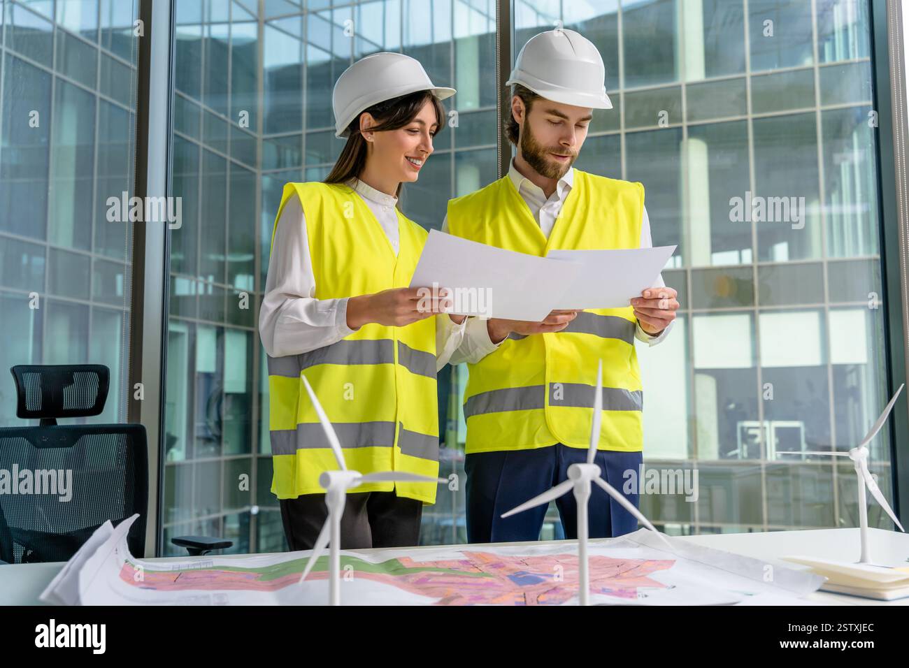 Two young engineers in yellow vests discussing new sustainability ...