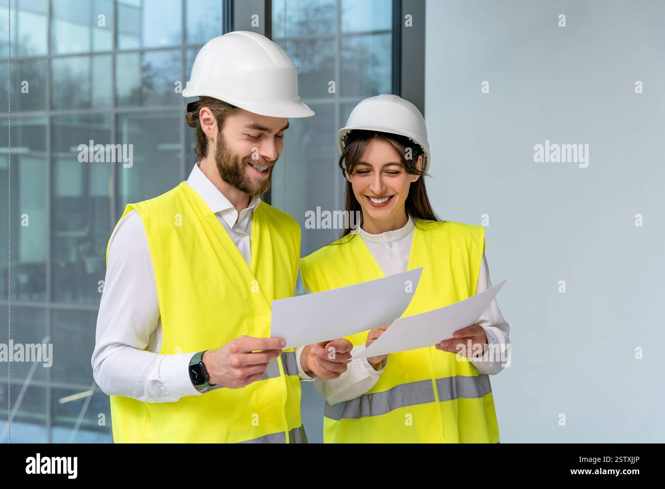 Two young engineers in yellow vests discussing new sustainability ...
