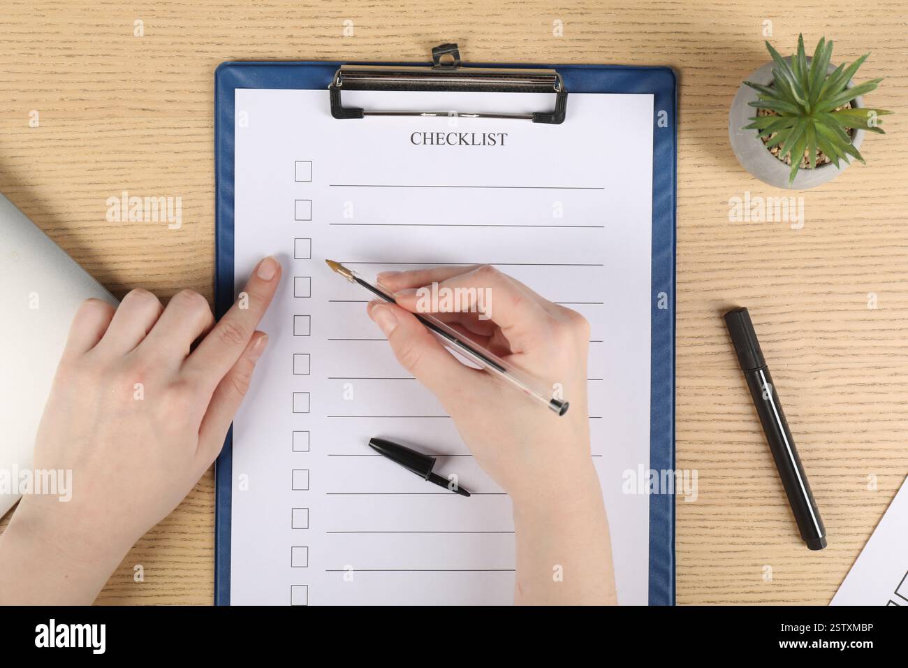 Woman filling Checklist with pen at wooden table, top view Stock Photo ...