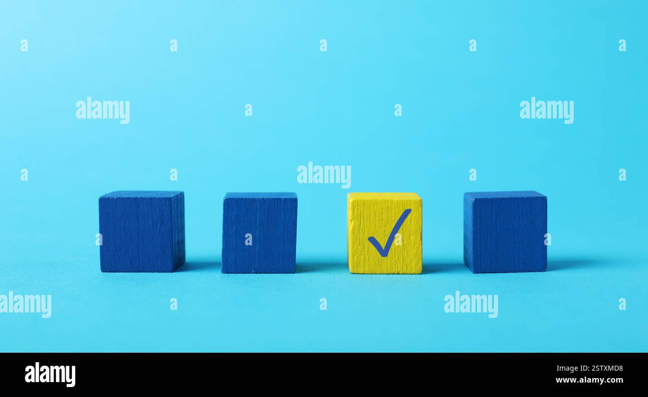 One yellow cube with check mark among others on light blue background ...