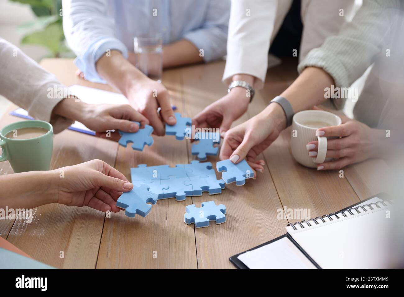 Unity concept. People putting puzzle pieces together at wooden table indoors, closeup Stock ...