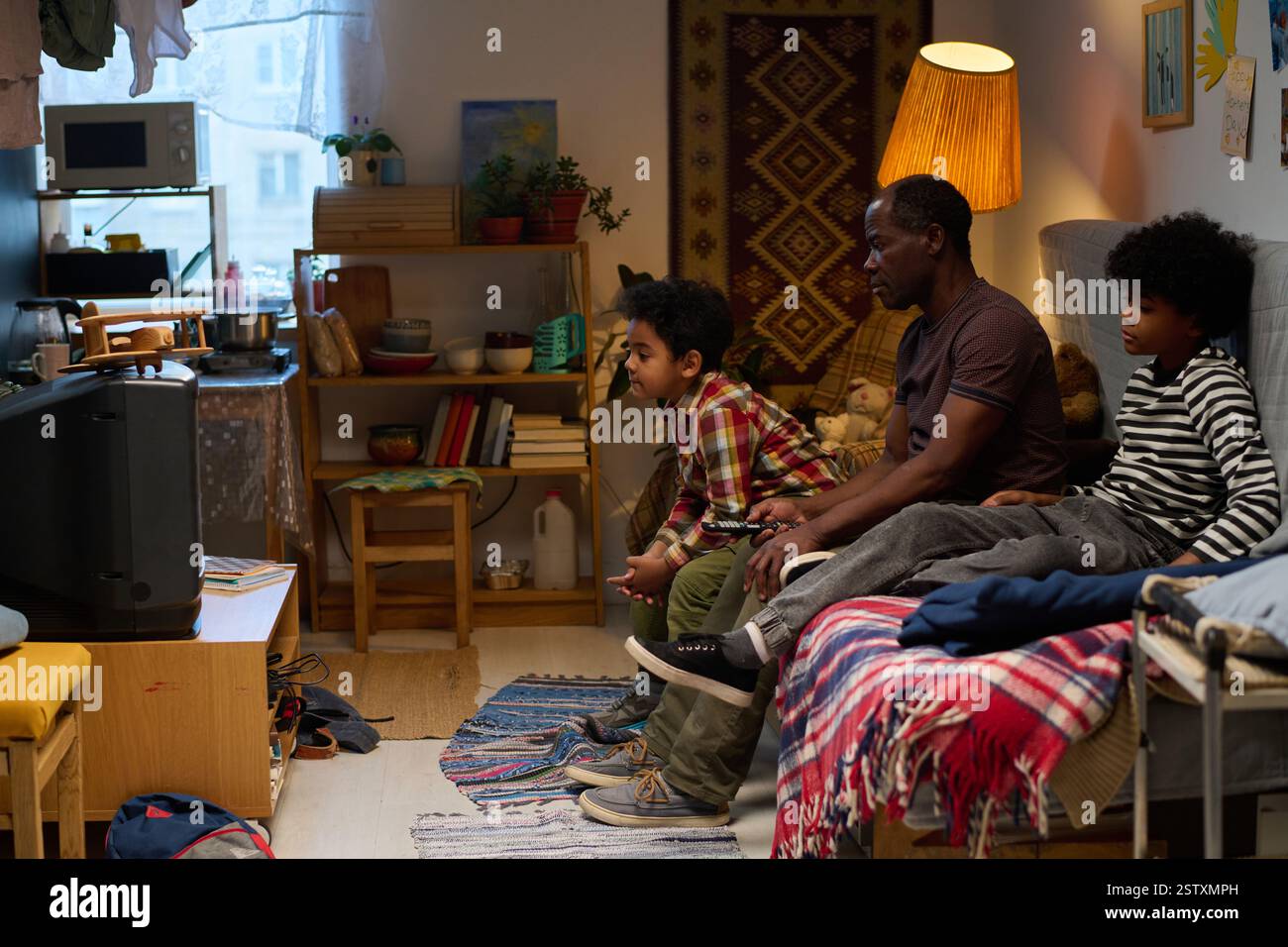 Family enjoying TV time in cozy living room with warm lighting, family ...