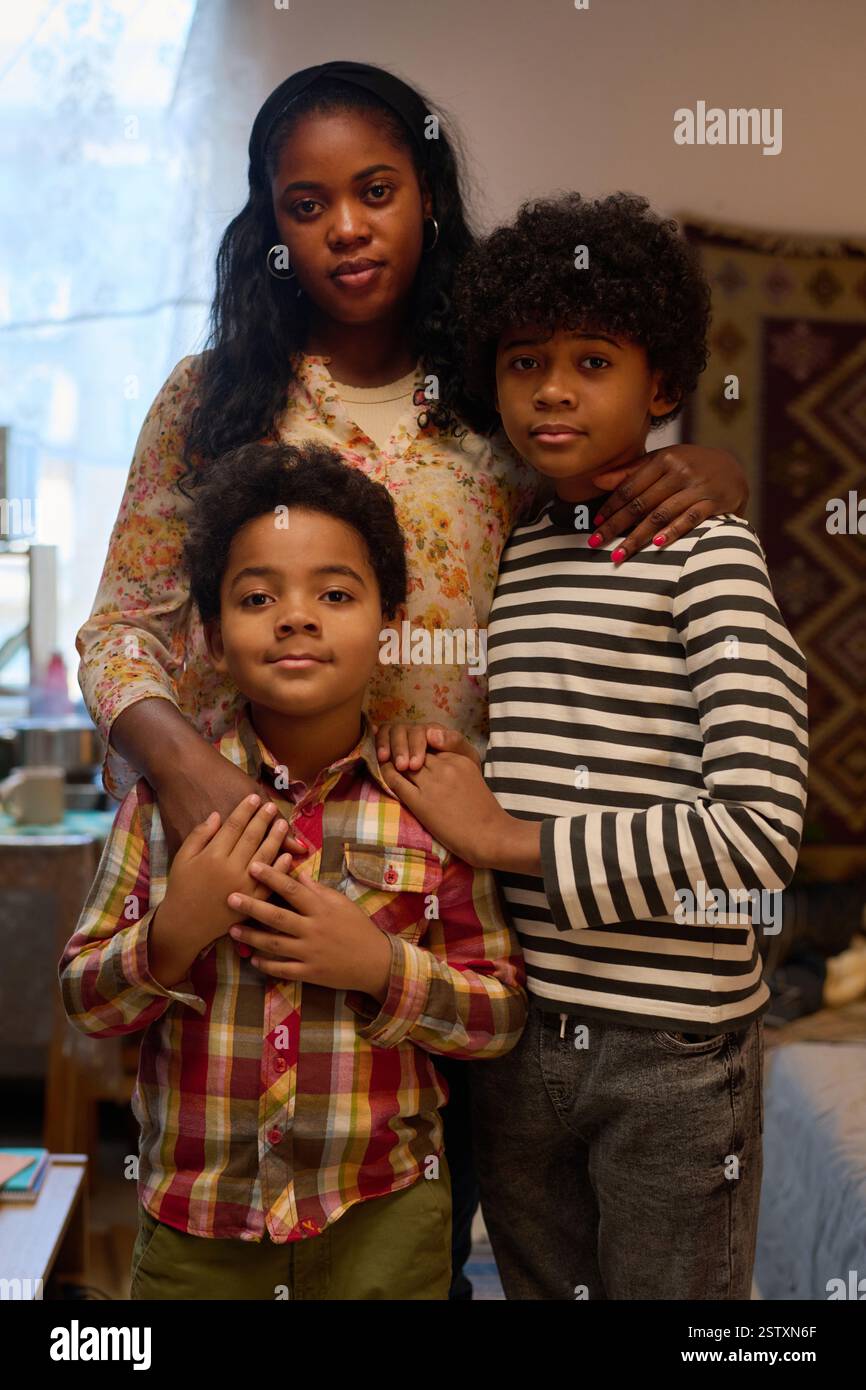 Mother standing with her two children in cozy home environment, creating heartfelt family moment ...