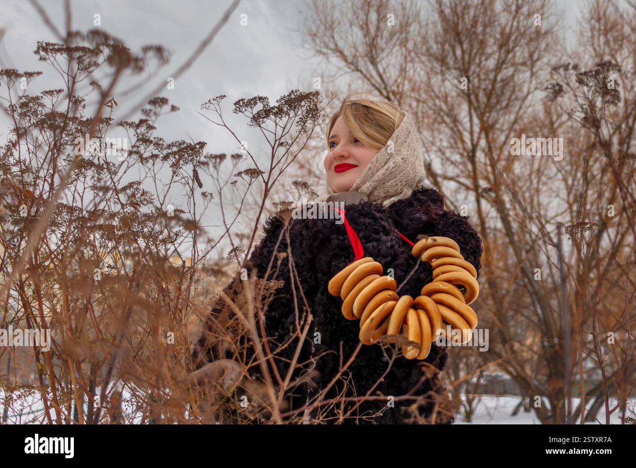 Russian woman in fur coat and folk down shawl with bagels. Shrovetide ...