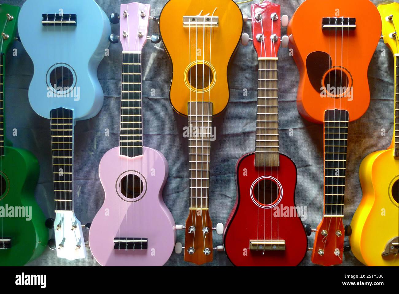 A vibrant row of small ukuleles in various bright colours, neatly lined ...