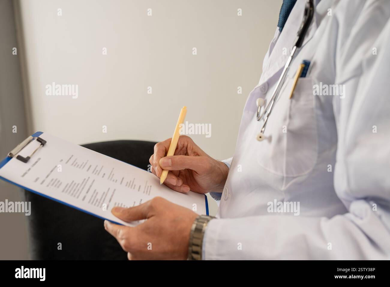 Doctor reviewing medical records on a clipboard in a hospital office ...