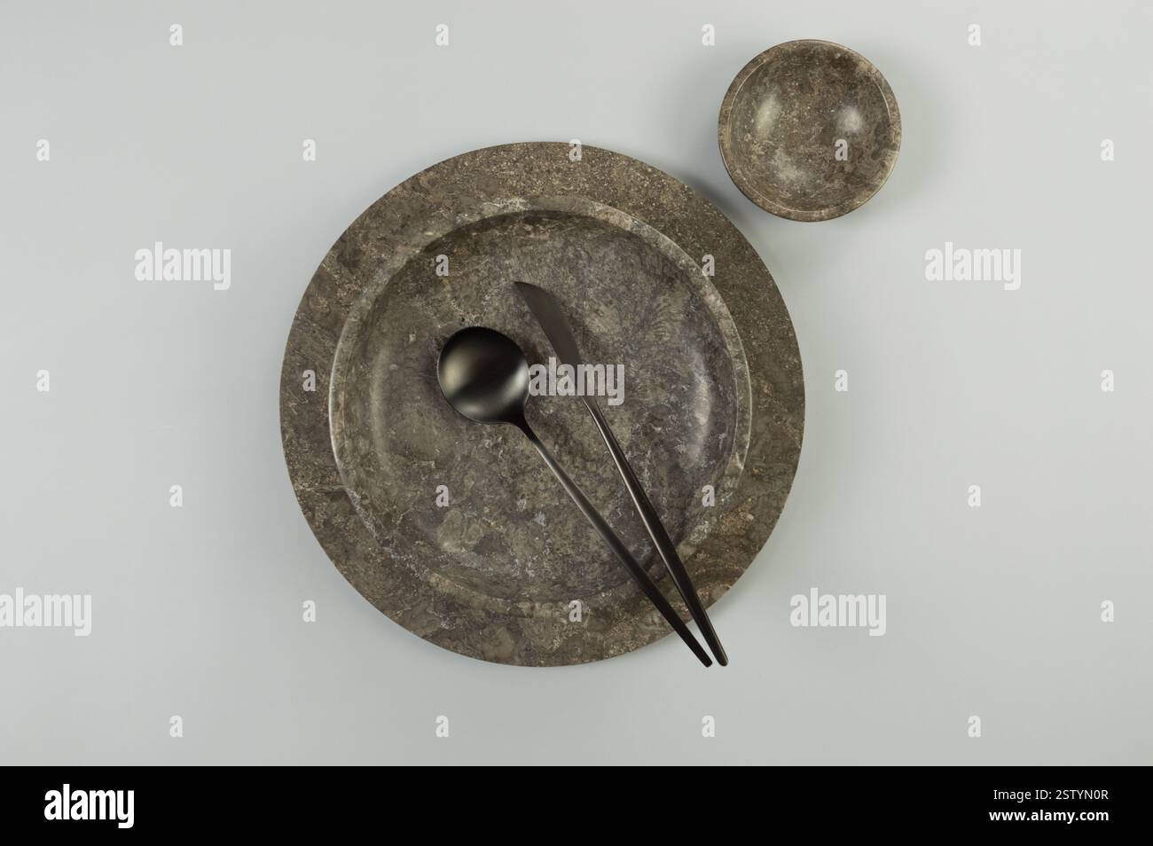 Top view of brown marble tray and plate, black cutlery on grey ...