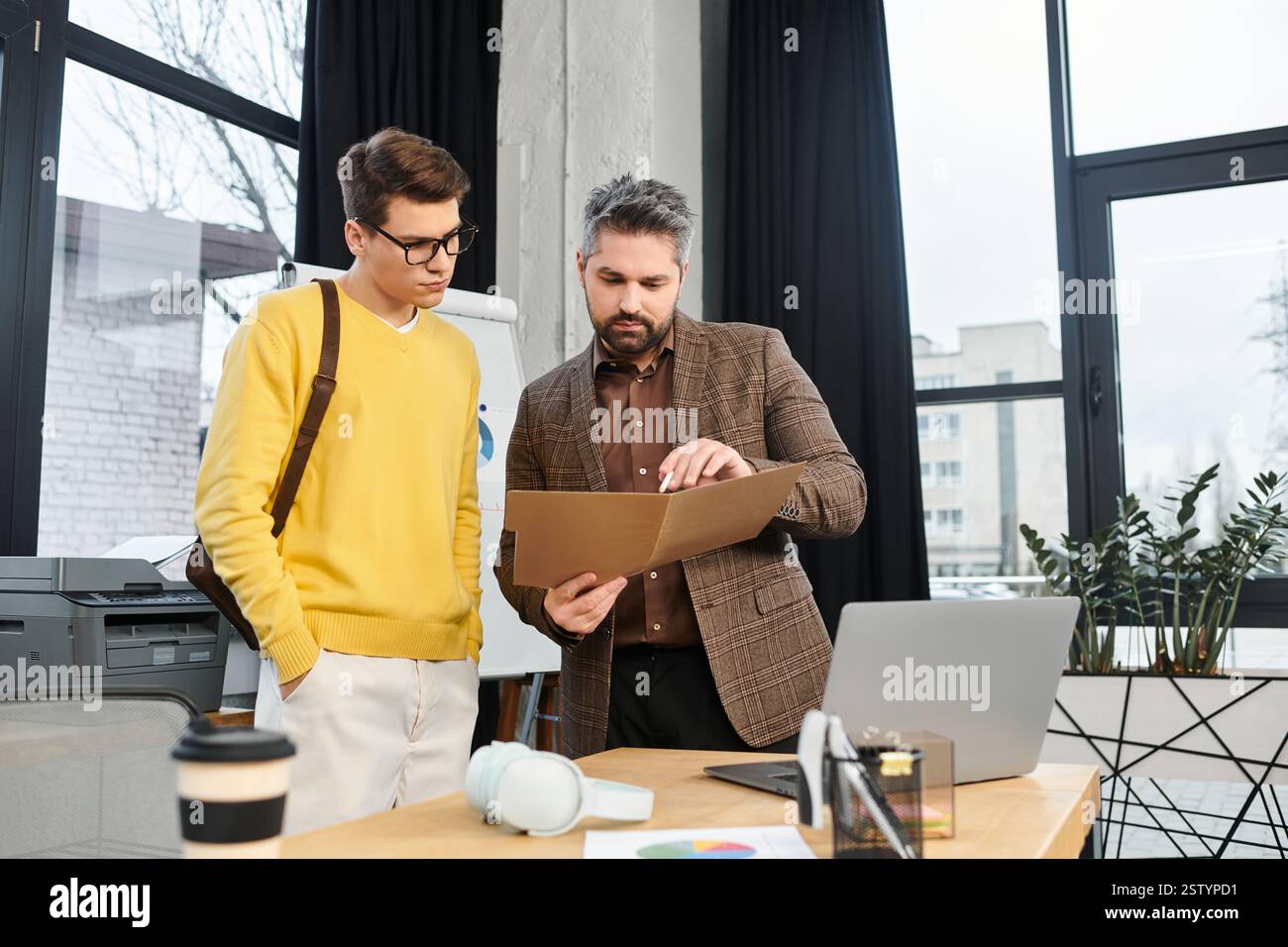A mentor helps a new team member review important documents at work on ...
