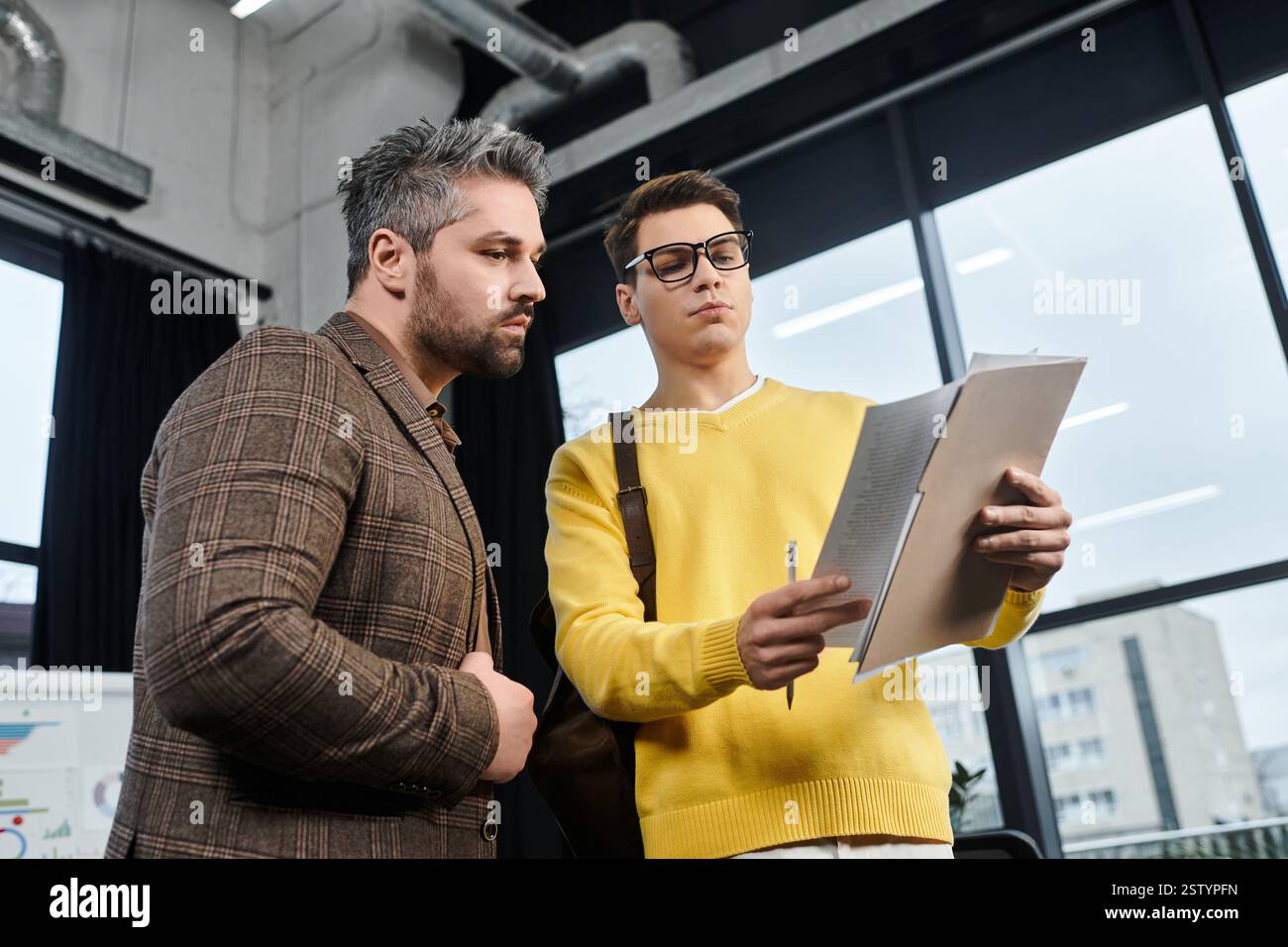 Two colleagues in formal attire review documents during onboarding in a ...