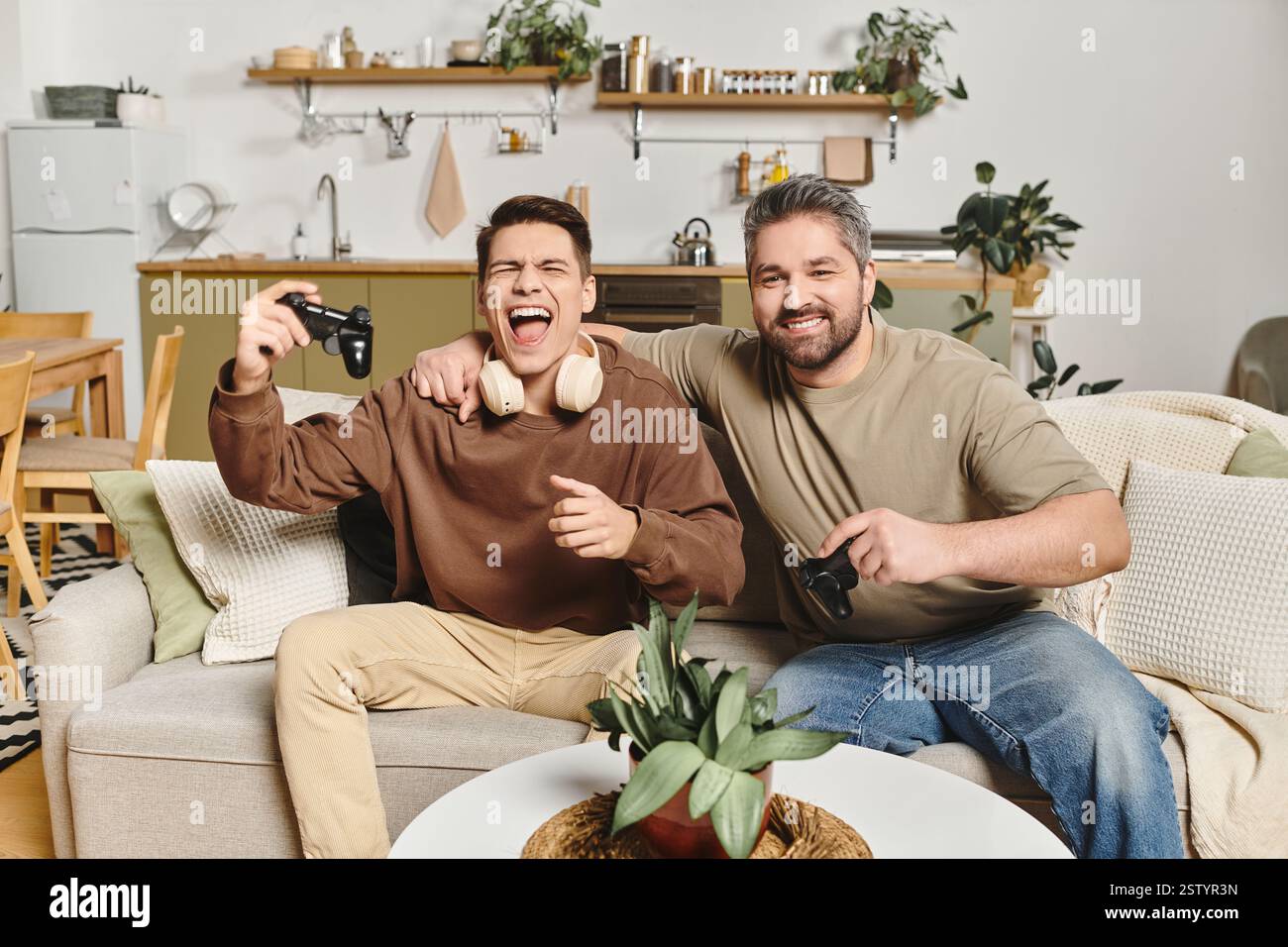 Two brothers celebrate their gaming victory at home, surrounded by warm ...