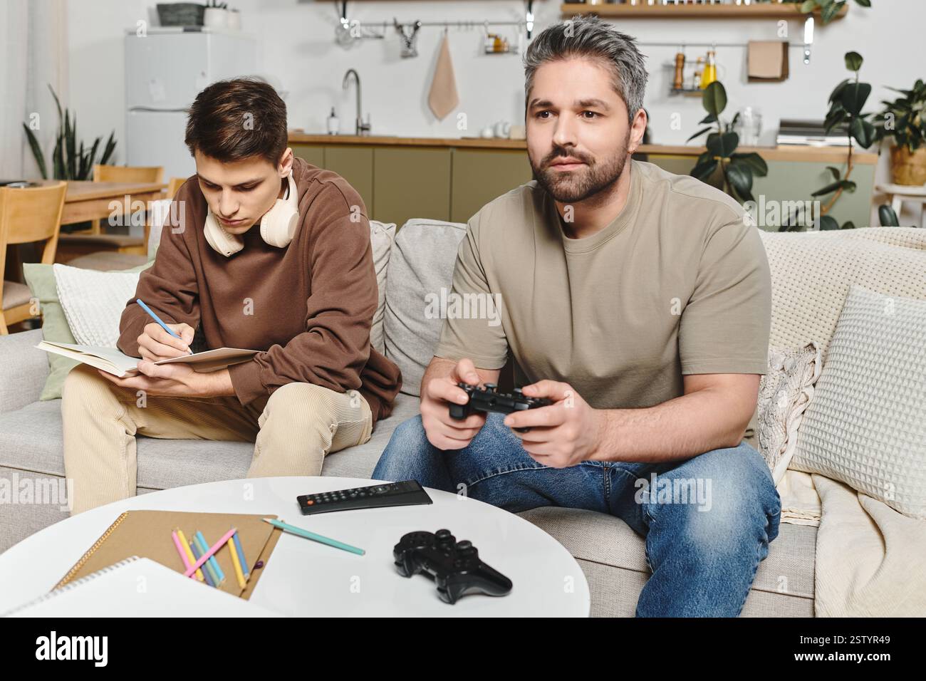 Two brothers enjoy time together, one playing a video game while the ...