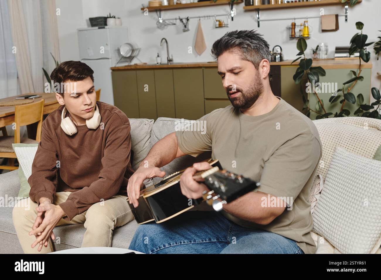 Two brothers enjoy a warm afternoon at home while learning guitar ...