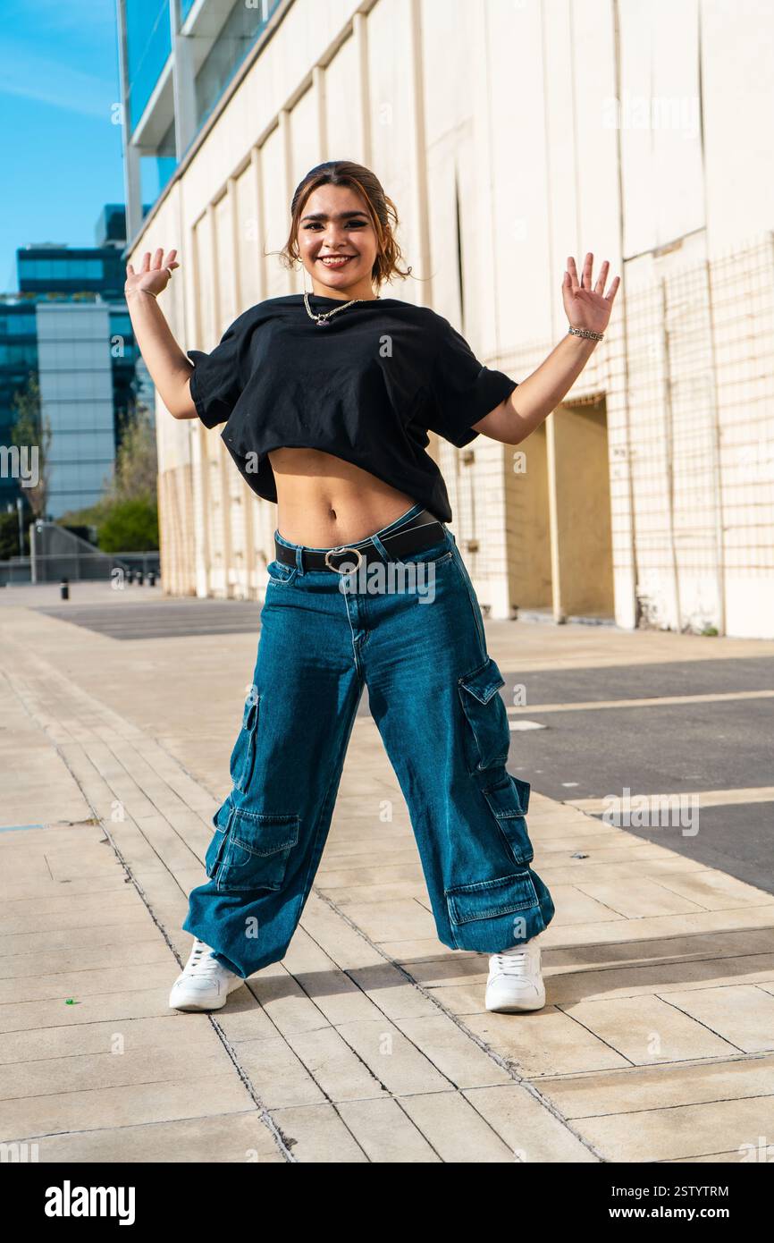 Young woman dancing energetically outdoors in urban setting Stock Photo ...