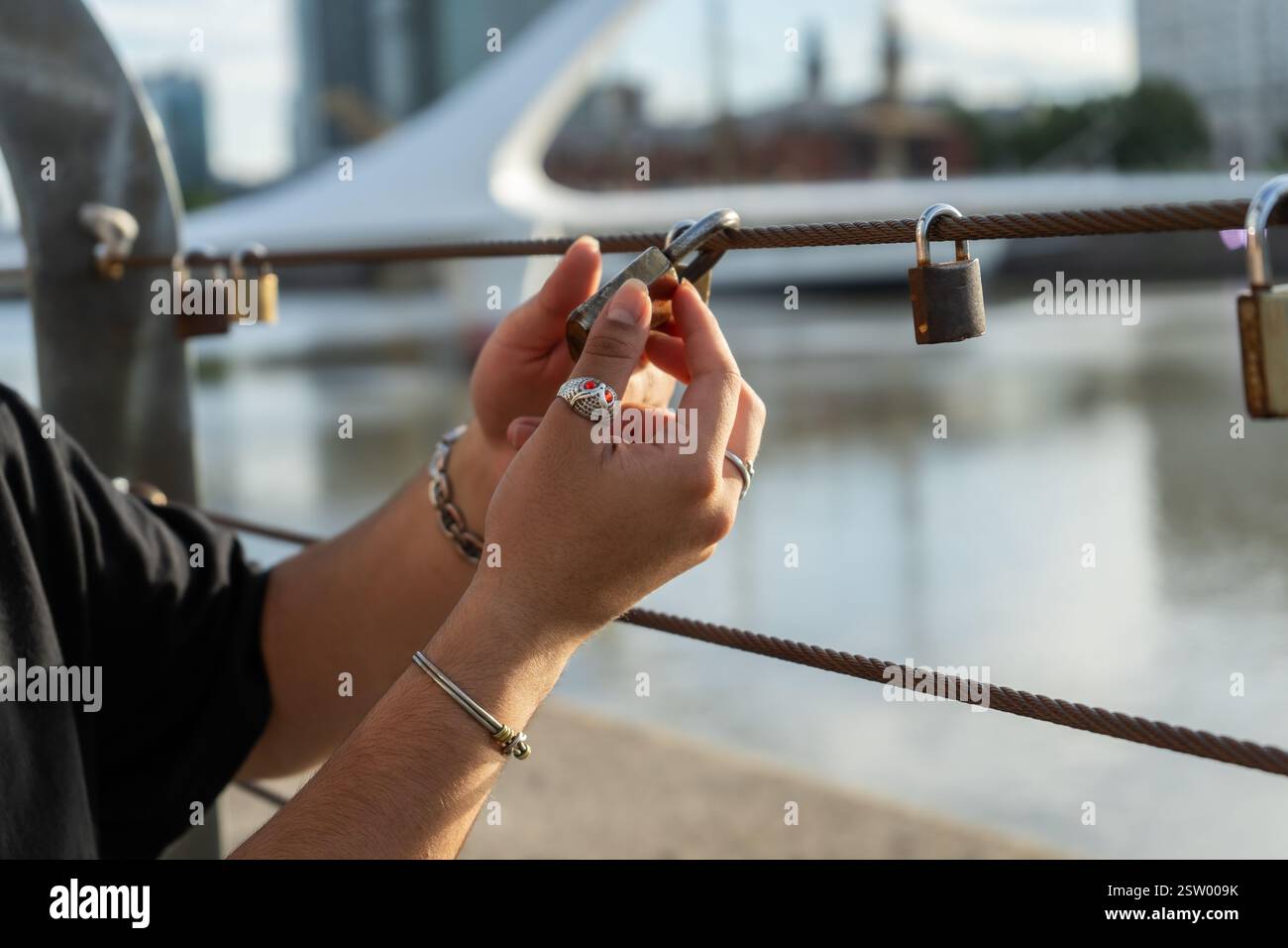 Hands securing a love lock onto a bridge cable, symbolizing enduring ...