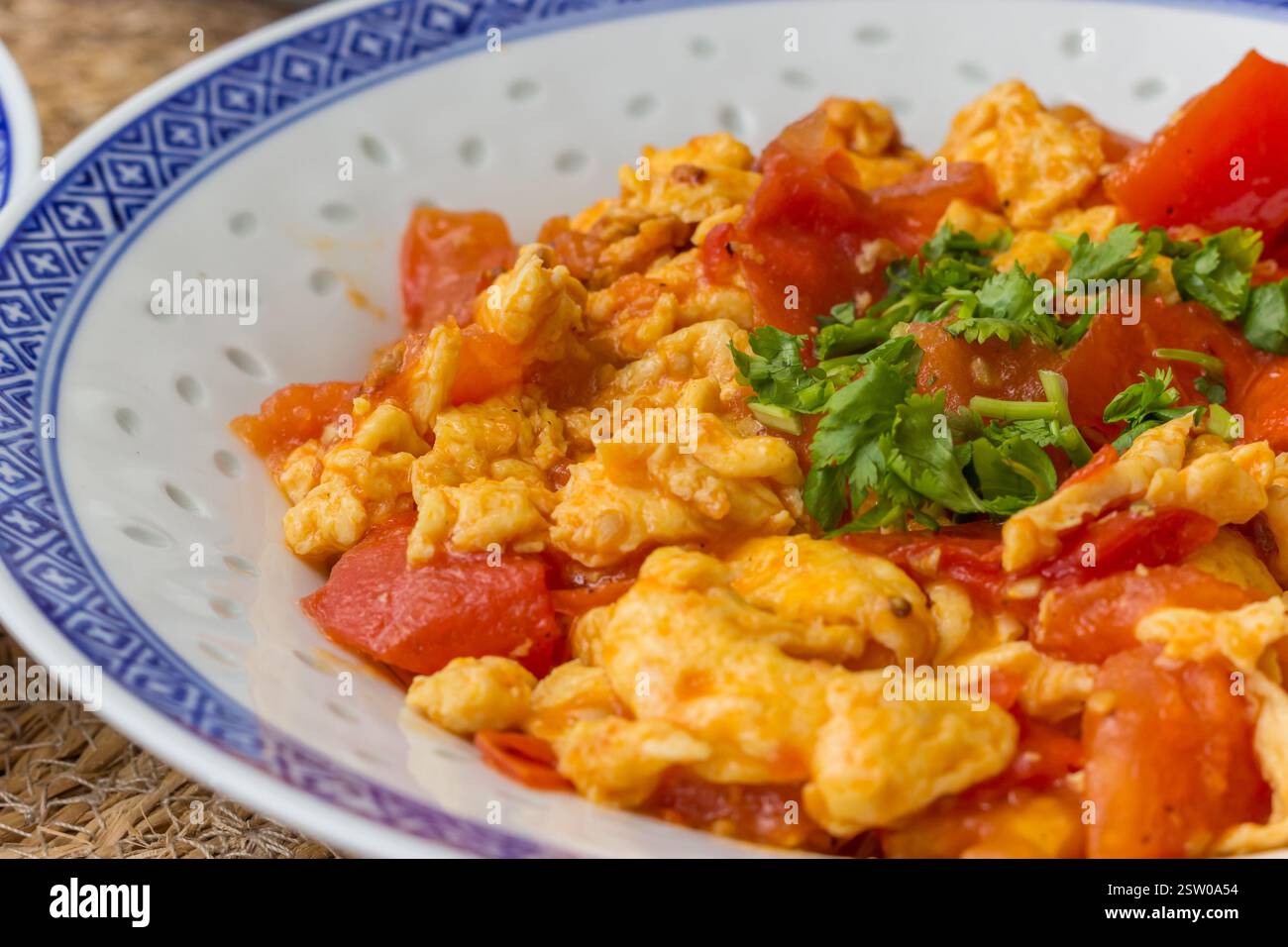 Asian dish with fried egg, tomato and cilantro on a traditional chinese ...
