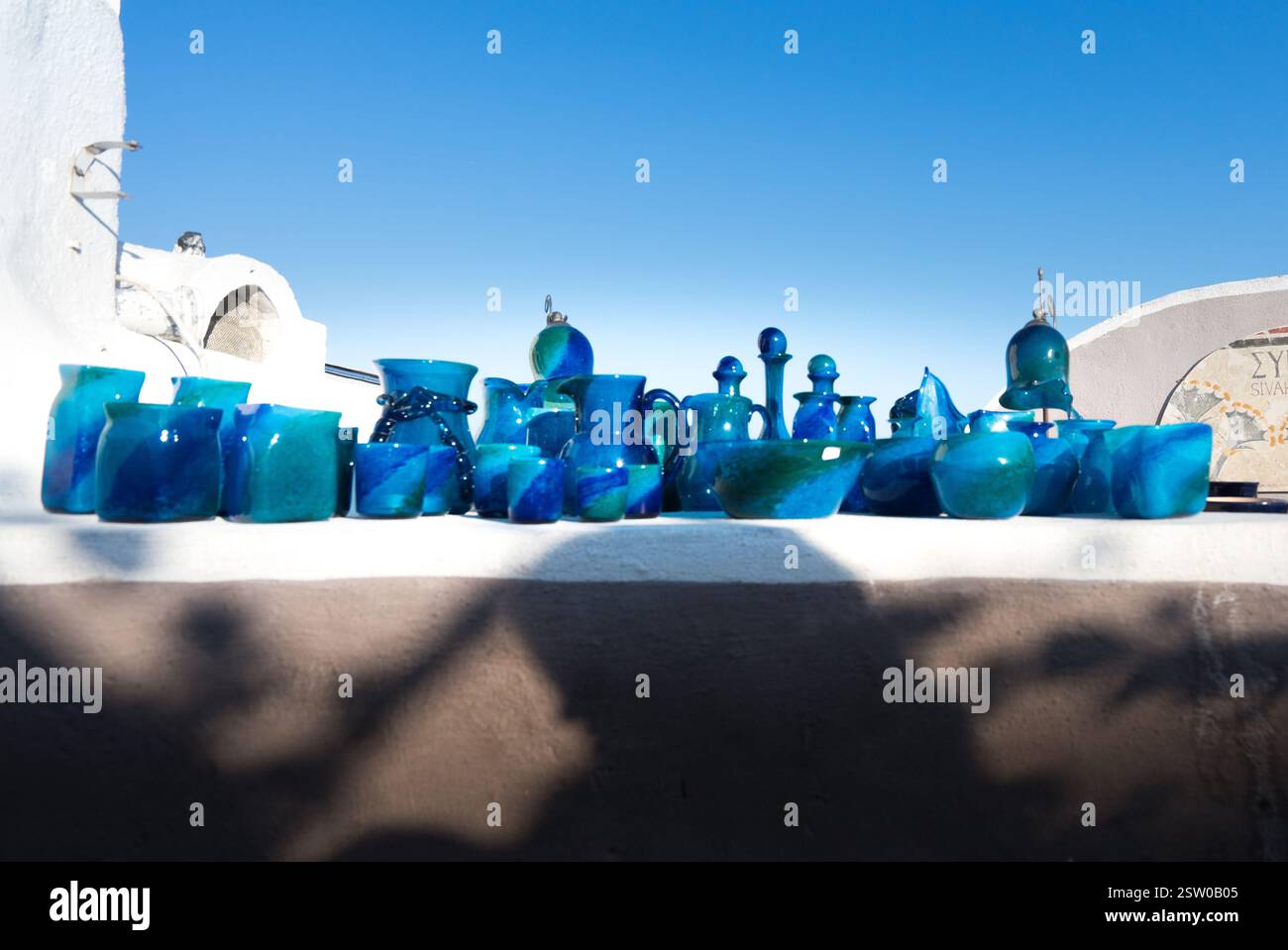 Collection of blue-green greek glassware sat on wall in santorini under ...