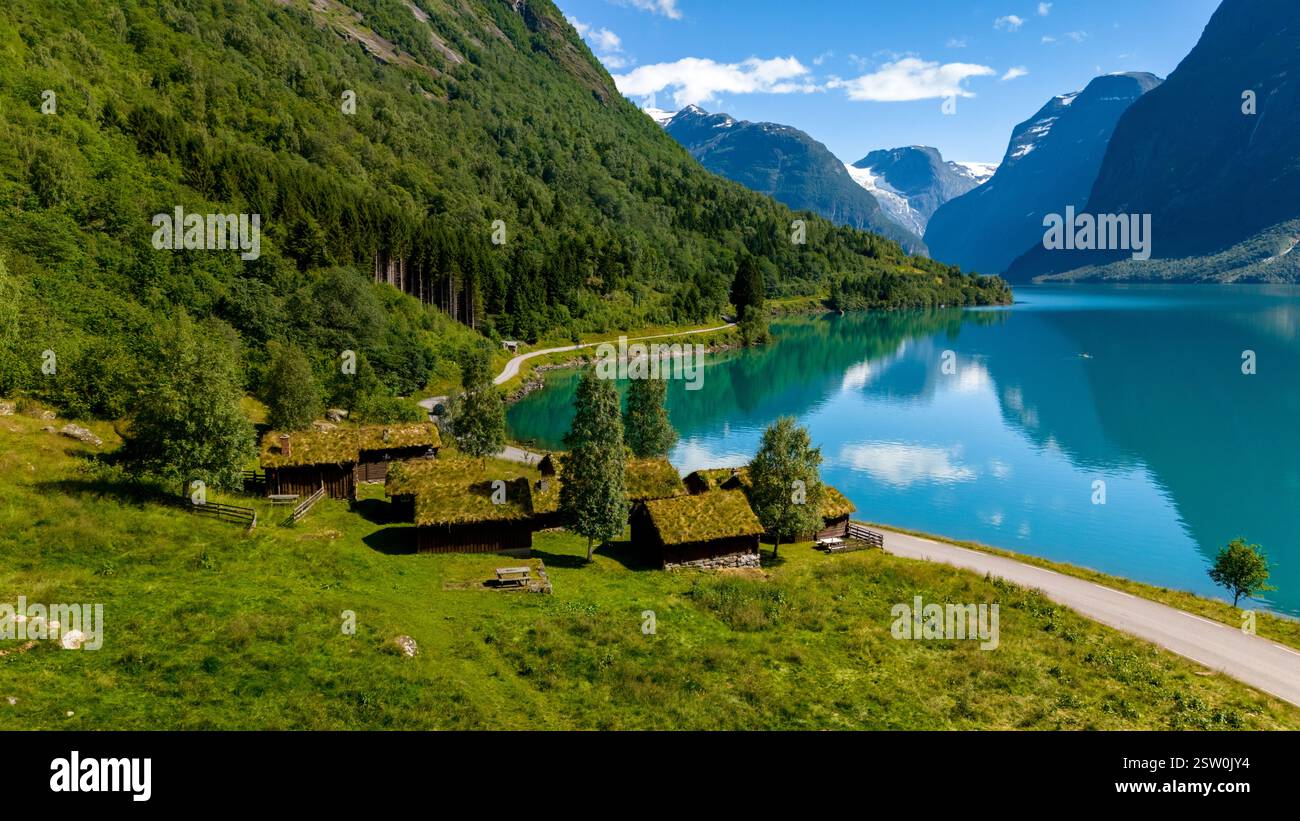 Green-roofed cabins rest on a grassy hillside overlooking a serene ...