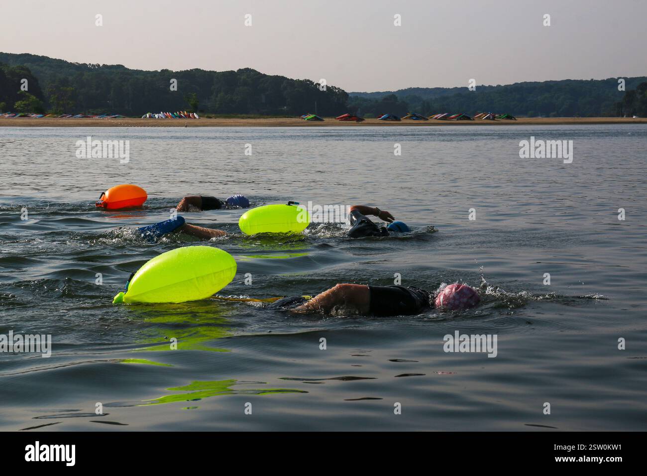 Swimmers glide through calm waters using floatation devices during a ...