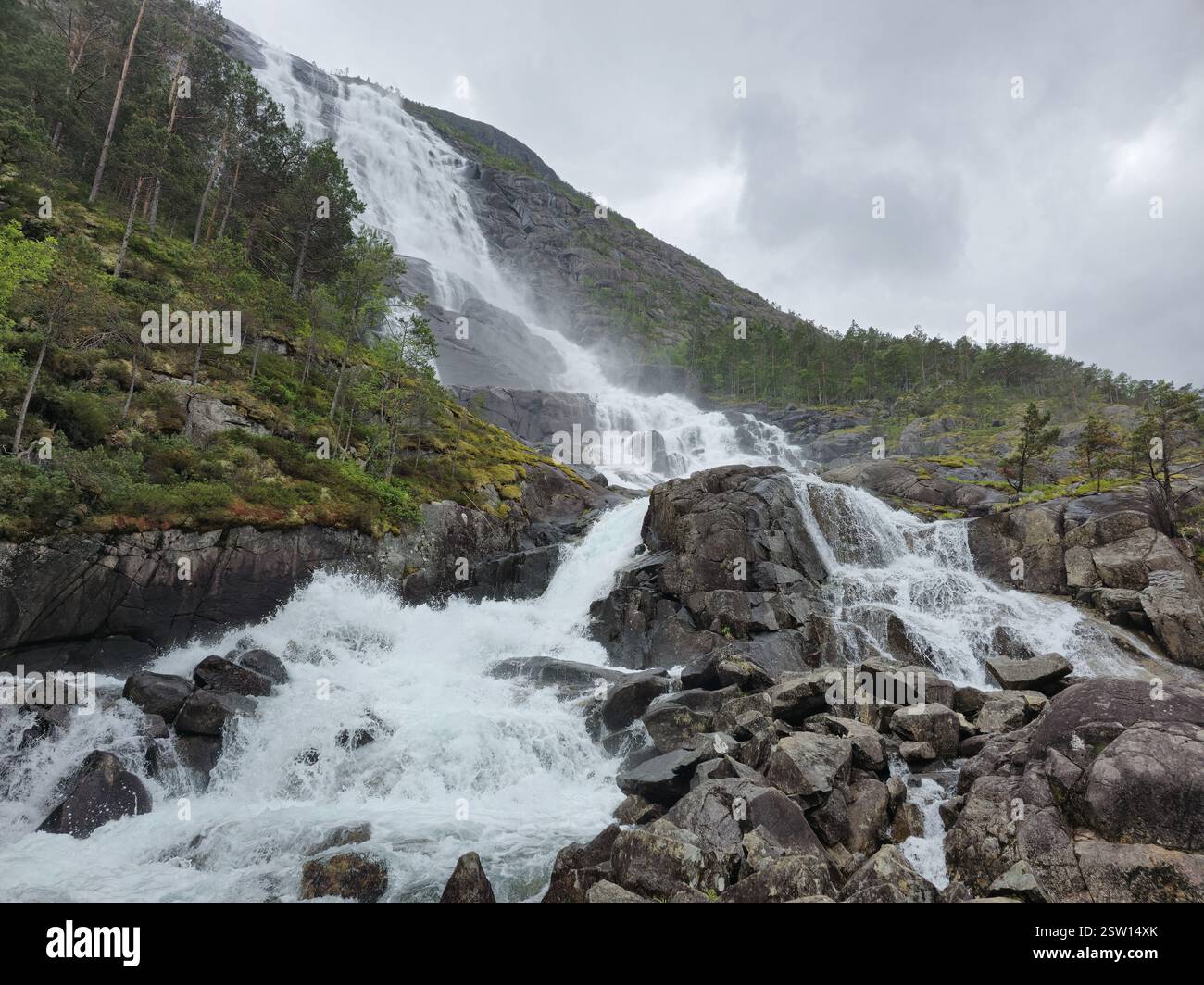 A powerful waterfall tumbles from steep, moss-covered cliffs ...