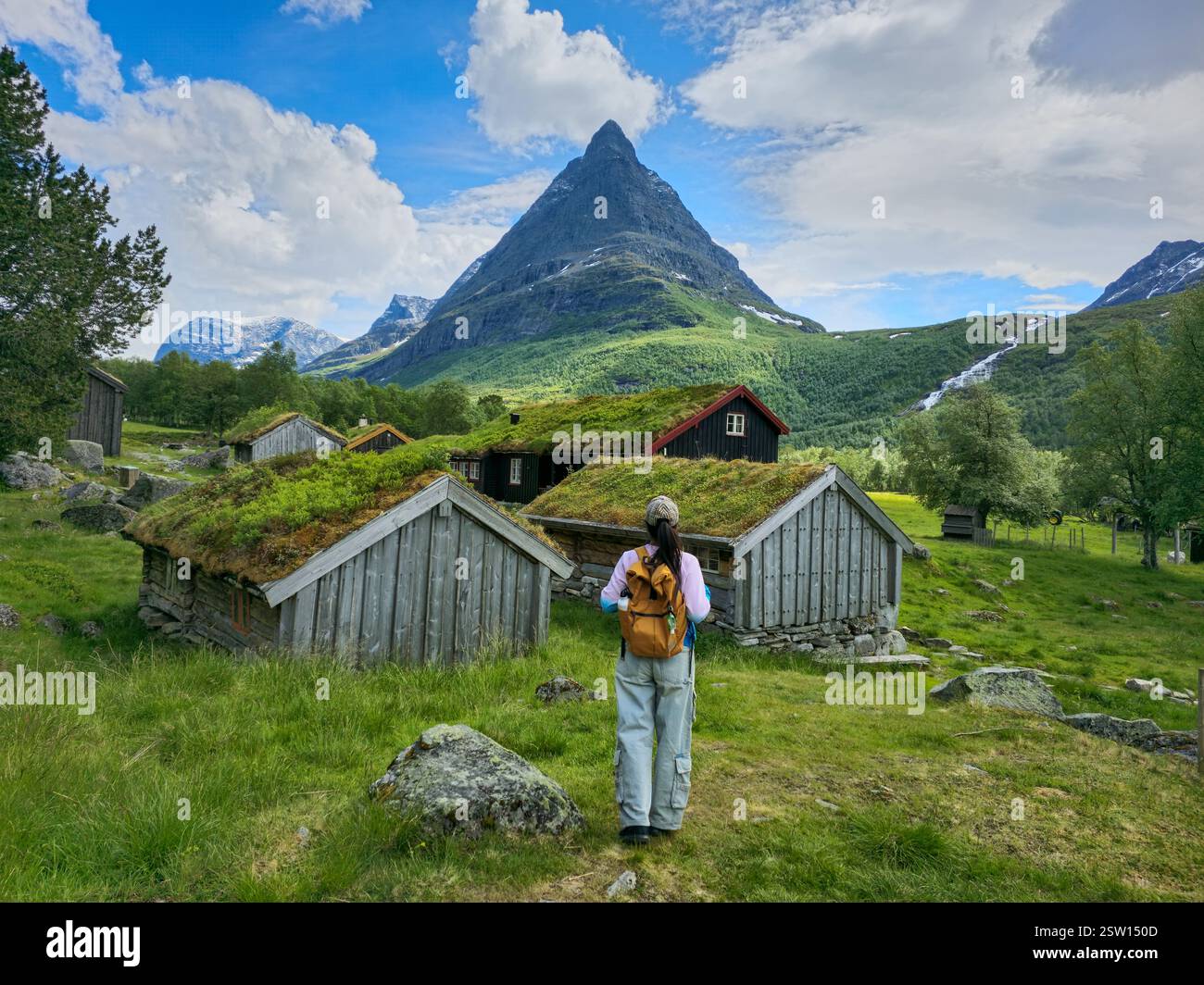 A traveler wanders towards charming turf-roofed houses beneath a ...