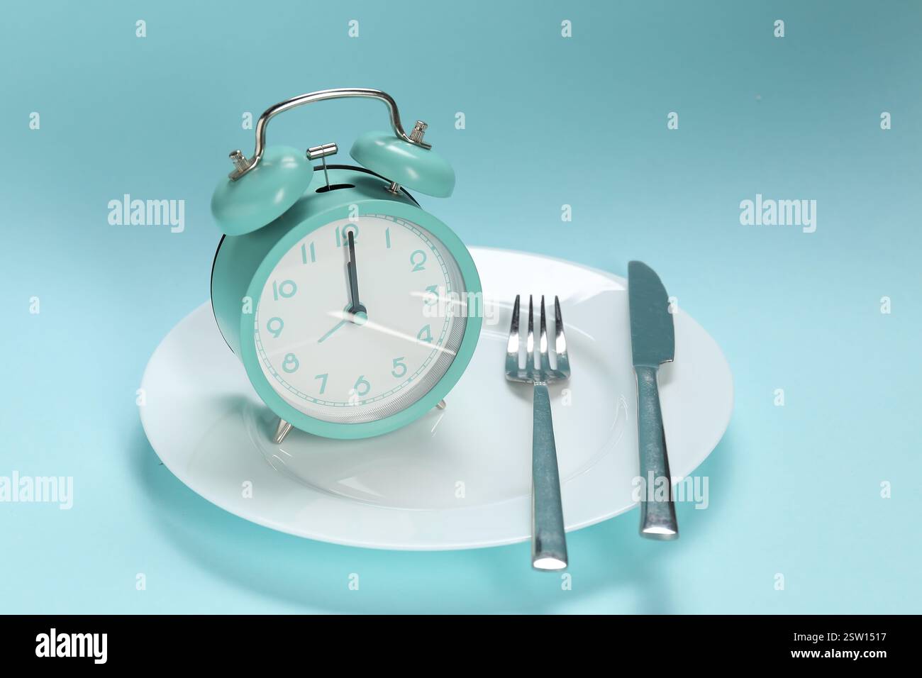 Alarm clock, plate and cutlery on light blue background Stock Photo - Alamy