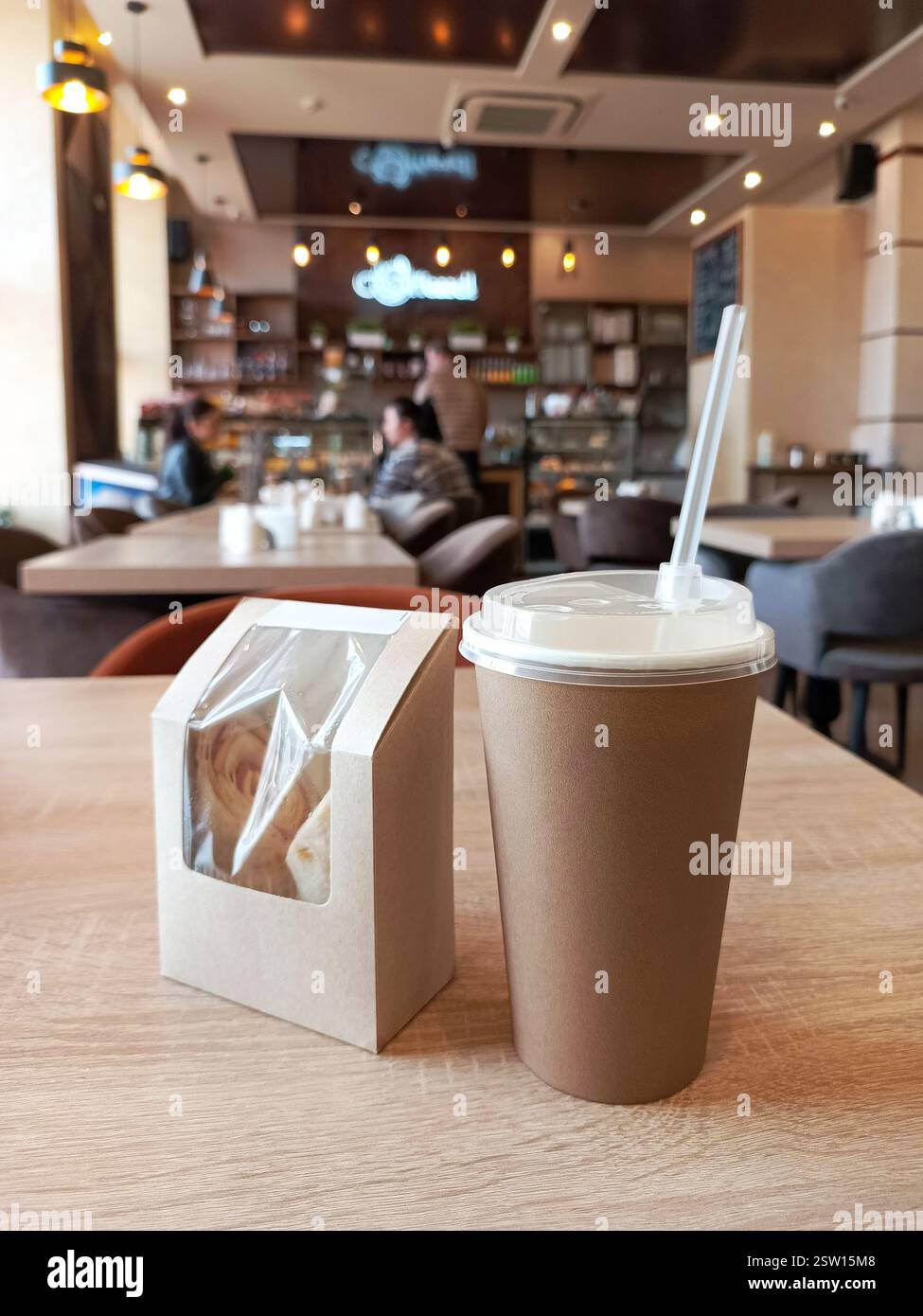 Take away coffee cup and rolls with ham and cheese on a table in the ...
