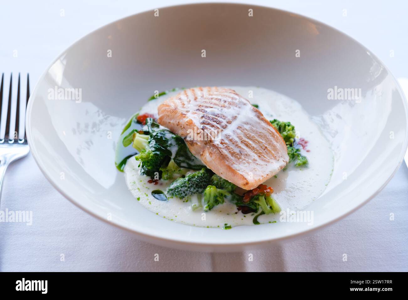 Pan seared fish fillet served over sauteed broccoli in a creamy sauce ...