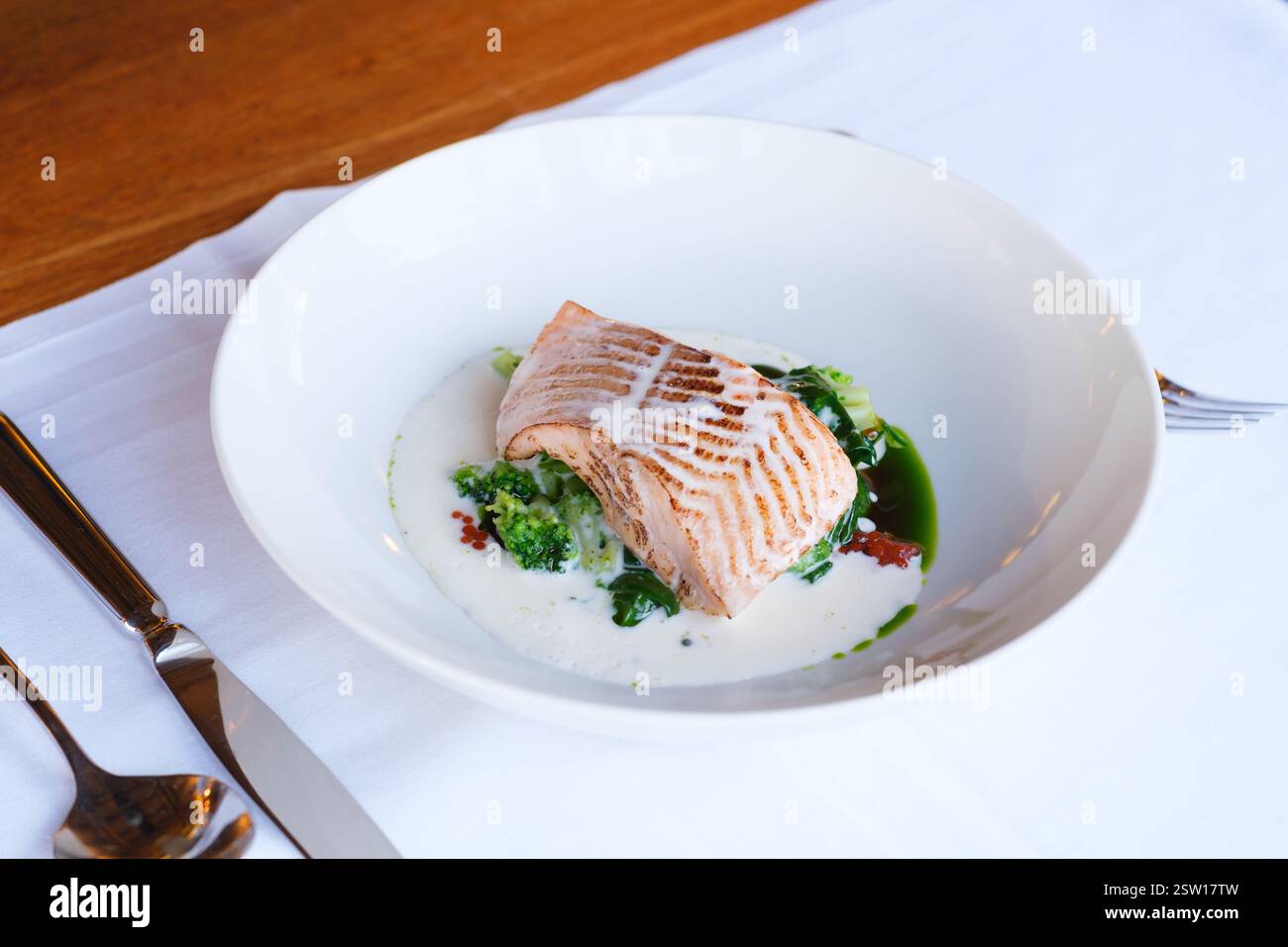Pan seared fish fillet served with creamy sauce and sauteed greens ...