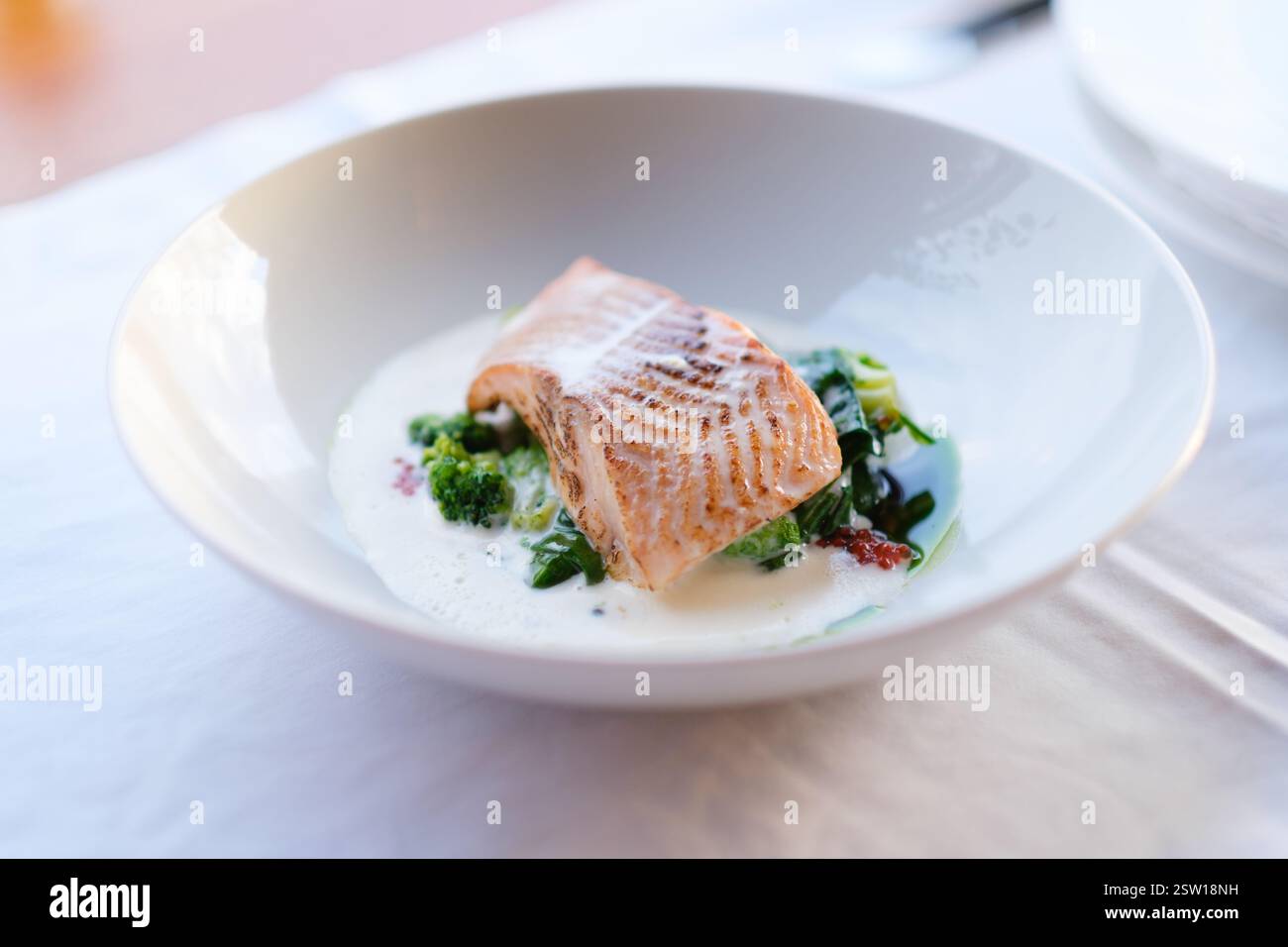 Pan seared salmon fillet served with creamy sauce and sautéed greens ...