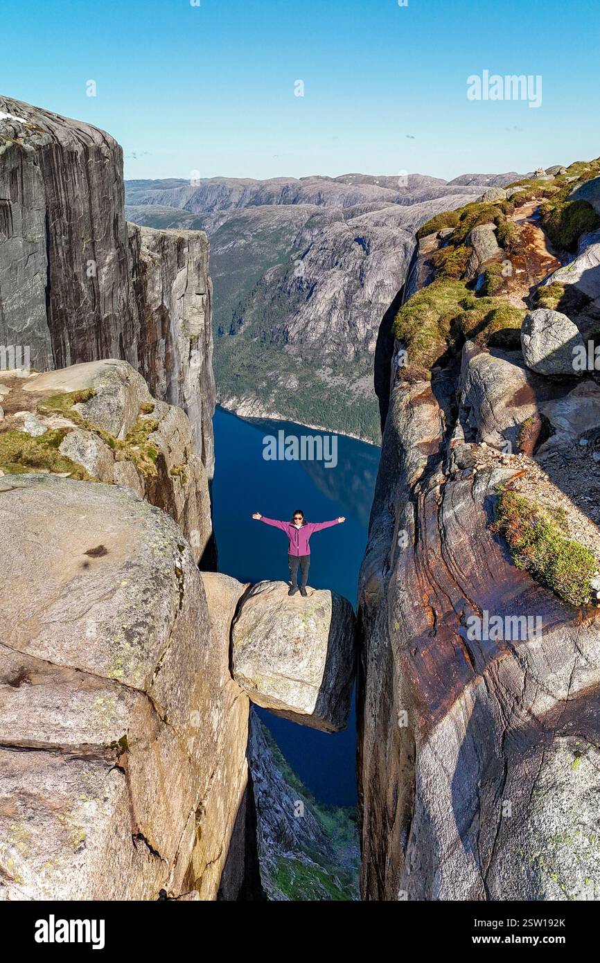 A lone adventurer embraces the breathtaking views atop kjeragbolten hi ...
