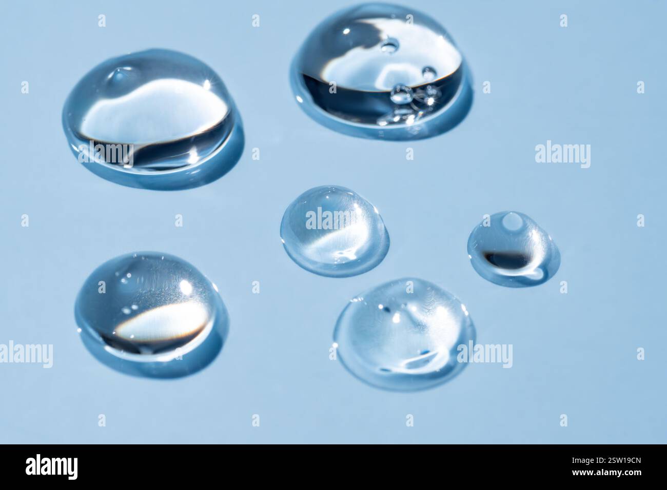 Pure transparent cosmetic gel drops on blue background, skin care ...