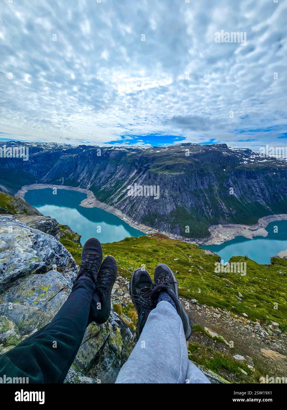 Two pairs of feet dangle over a breathtaking fjord in Norway ...