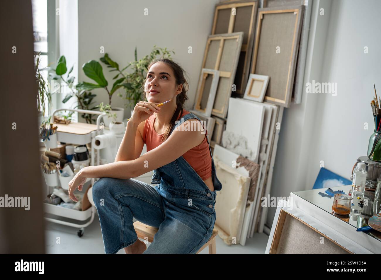 Happy thoughtful woman painter at art creative workshop workplace looking up with enthusiasm ...